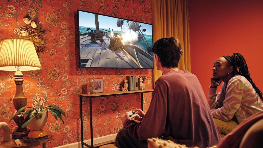 Dwie osoby w salonie grają na konsoli Xbox na telewizorze Smart TV firmy Samsung
